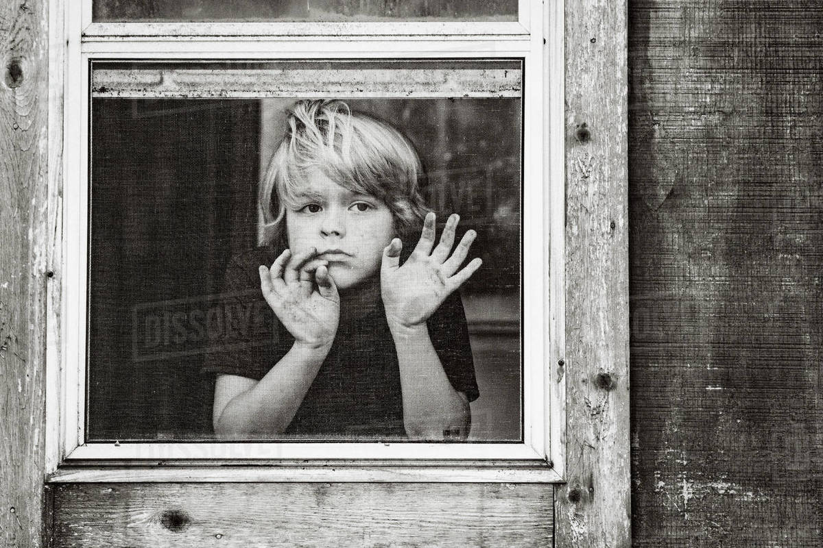 Portrait serious boy looking out window - Stock Photo - Dissolve
