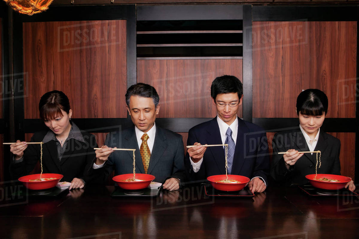 Japanese business people in suits eating ramen with chopsticks in ...
