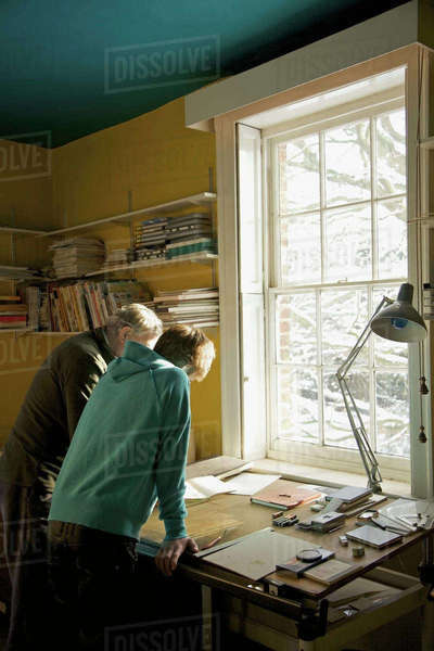Back view of two men leaning over a desk - Royalty-free Stock Photo ...