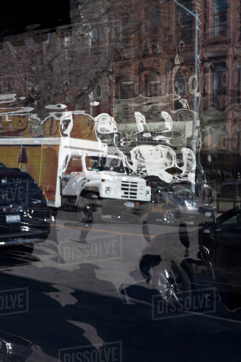 A city street scene distorted in the reflection of a tinted window ...