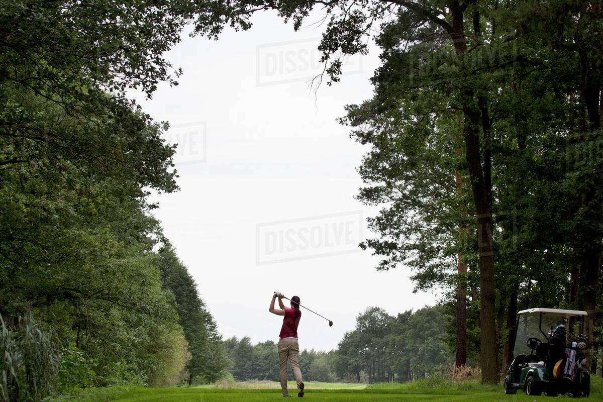 A female golfer teeing off, rear view - Royalty-free Stock Photo | Dissolve